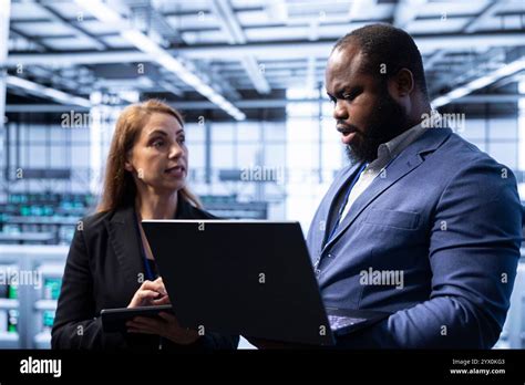 Employee In Server Hub Showing Manager Recovery Plan On Laptop Monitoring Energy Consumption