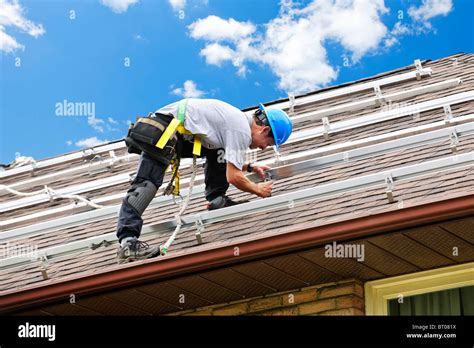 man installing rails for solar panels on residential house roof stock