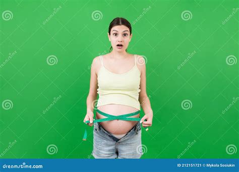 Cropped Image Of Expecting Mother In Unzipped Jeans Measuring Her