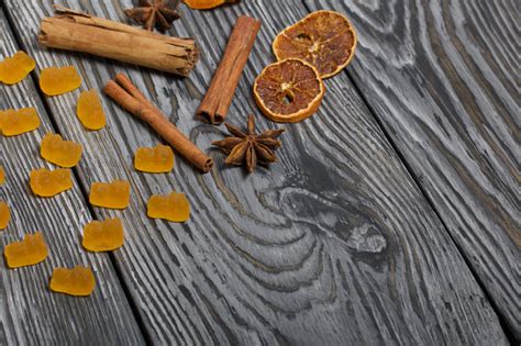 젤리 츄잉 과자 오렌지 계피 스틱 아니스 별의 말린 조각 검은 색과 흰색으로 칠해진 기모 소나무 판에 흩어져 있습니다 계피에 대한 스톡 사진 및 기타 이미지 Istock