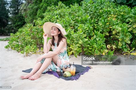 선글라스와 바다 모자를 쓰고 있는 아름 다운 여 인은 오렌지 주스를 마시고의 자에 앉 습니다 해변에서 가방에 대한 스톡 사진 및 기타 이미지 Istock