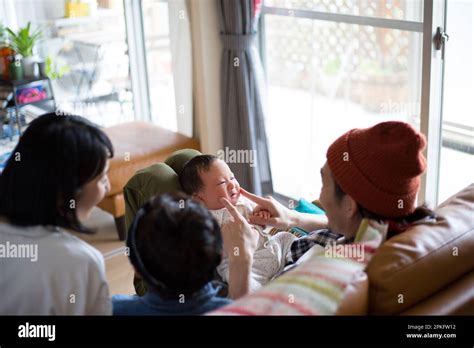 A Father With His Baby On His Lap While His Older Babe And Mother Watch On Stock Photo Alamy