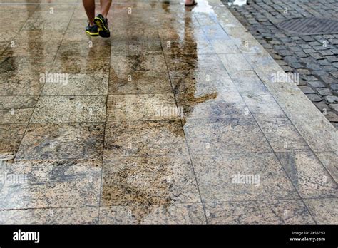 Reflection On The Wet Ground From The Rain Of Pedestrians Passing On The Sidewalk Rainy Day
