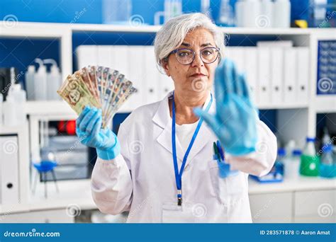 Middle Age Woman With Grey Hair Working At Scientist Laboratory Holding