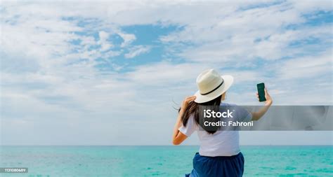 젊은 아시아 여성 나무 부두에서 셀 카를 복용 밀 짚 모자 사용 스마트 폰을 착용 열 대 파라다이스 비치에서 여름 휴가 휴일에