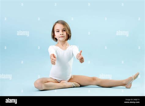 Tired Girl In A White Leotard Sitting In Half Splits Giving Thumbs Up