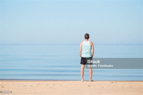 모래 위에 홀로 서서 따뜻한 여름 아침에 잔잔한 바다와 밝은 푸른 하늘을 응시하는 청년 정서적 긍정적 영감 텍스트 인용 또는 말을위한 빈 장소 다시 보기입니다 개념에 대한