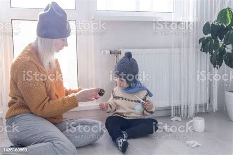 노란 스웨터를 입은 젊은 어머니는 아이의 온도를 측정하고 질병에 대한 약을 제공합니다 2 3 살에 대한 스톡 사진 및 기타