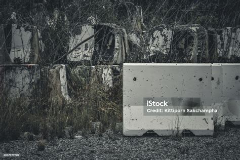 부서진 콘크리트 장벽 블록로드 폐허는 어두운 톤의 영화 같은 배경을 배경으로 버려진 폐차장에 높이 쌓여 있습니다 가장자리에 대한