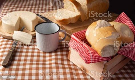 브라질의 아침 식사 테이블에는 갈색과 베이지 색 체크 무늬 식탁보 어두운 배경 선택적 초점에 빵 치즈 커피 컵 및 액세서리가