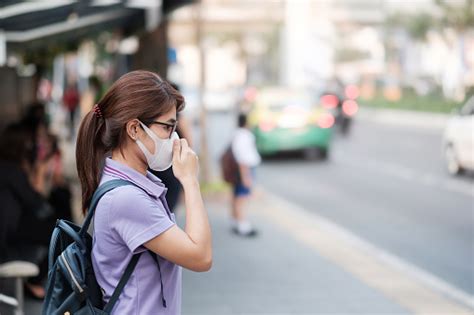 N95 호흡기 마스크를 착용한 젊은 아시아 여성이 교통 및 먼지 도시로부터 Pm25를 보호하고 걸립니다 의료 및 대기 오염 개념