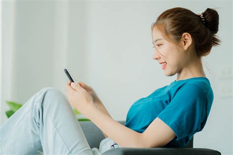 귀엽고 아름다운 아시아 여성이 소파에 누워 소파에서 휴식을 취하며 집에서 행복하게 소셜 미디어를 재생합니다 놀기에 대한 스톡 사진 및 기타 이미지 Istock