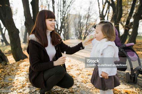 행복한 엄마와 아이 소녀의 초상화를 닫고 화창한 날에 아름다운 가을 공원에서 재미있게 놀고 웃고 Litlle 소녀가 비누 거품을