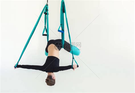 年轻苗条的女人在健身工作室的白色背景上用伸出的双手练习飞瑜伽蝴蝶高清图片下载 正版图片503527395 摄图网