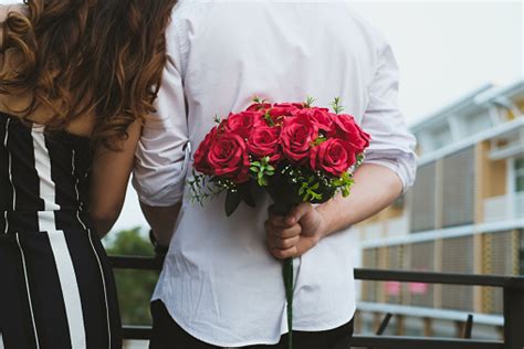 남자의 그의 뒤의 뒤에 빨간 장미 꽃다발을 들고 남자 친구 깜짝 발렌타인의 날에 꽃과 여자 친구 축 하 기념일 사랑 관계 개념