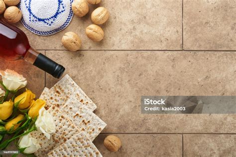 유월절 축하 개념입니다 Matzah 코셔 레드 와인 호두 흰색과 노란색 장미 모래 색깔 오래된 타일 벽 배경에 전통적인 의식