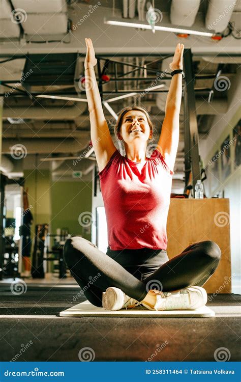 Plus Size Girl Sit On Mat In Fitness Gym With Crossed Legs And Raised