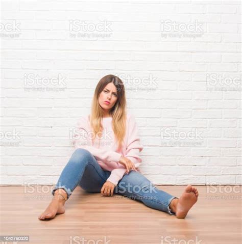 흰색 벽돌 벽 회의론 및 교차 팔과 얼굴에 긴장 Disapproving 식 바닥에 앉아 젊은 성인 여자 부정적인 사람입니다 감정에 대한 스톡 사진 및 기타 이미지 Istock