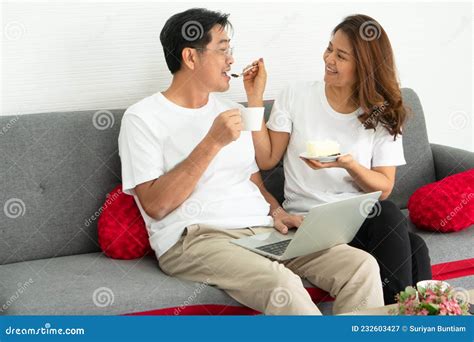 Loving Mature Wife Feeding Middle Aged Husband In The Living Room Stock