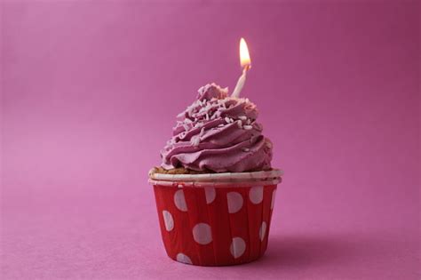 구운 촛불이 달린 크림 핑크 라일락 뚜껑이 있는 케이크 컵케이크 바구니 기념일 1 년 휴일 생일 텍스트 분홍색 배경에 대 한