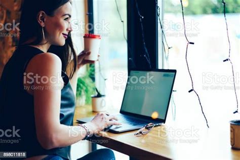 귀여운 블로거 행복 가제트와 함께 테이블에 앉아 맛 있는 커피와 함께 여가 시간을 즐기는 세련 된 옷을 입은 긍정적인