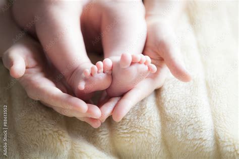 Mother Holding With Her Hands The Feet Of Her Naked Newborn Like A