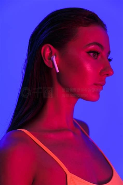 耳机高清图片穿着紧身衣内衣的性感性感女人，用耳塞听音乐，耳机隔离在紫罗兰色霓虹灯墙上产品实拍免费下载格式417像素编号