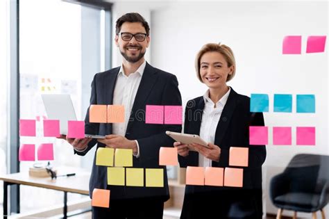 Business Professionals Brainstorming Ideas With Sticky Notes On Glass