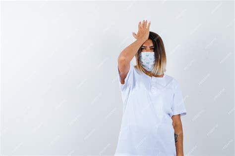T 셔츠 마스크에 머리에 손을 유지하고 건망증 전면보기를 찾고 젊은 여성의 Ortrait 무료 사진