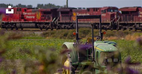 트랙터가 기차를 배경으로 들판에 주차되어 있습니다 사진 Unsplash의 무료 삼각주 이미지