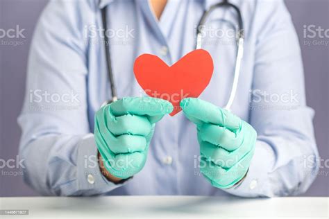 병원이나 클리닉에서 회색 배경의 의자에 앉아 있는 동안 빨간 종이 심장 모양을 보여주는 의사의 손 개념에 대한 스톡 사진 및 기타 이미지 Istock