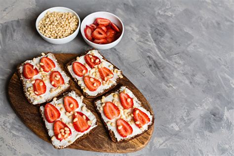 건강한 아침 식사 회색 콘크리트 배경에 딸기 소나무 견과류와 치즈와 검은 빵 본격적인 라이프 스타일 이미지입니다 플랫 레이 복사