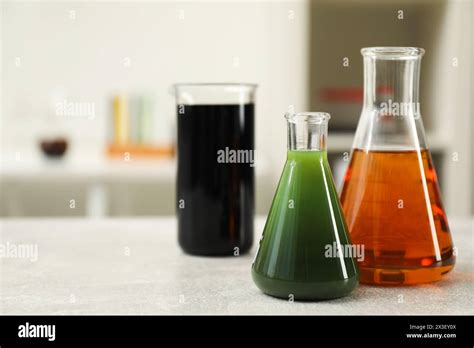 Flasks And Beaker With Different Types Of Crude Oil On Light Grey Table