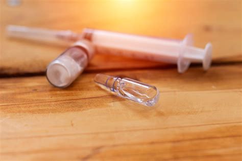 주입을위한 의학 병 예방 접종을위한 의료 용 유리 병 및 주사기 치료 실험실 병원 또는 나무 테이블 배경에 격리 된 약국