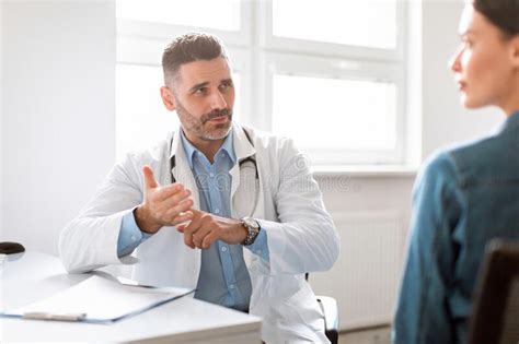 Middle Aged Male Doctor Having Conversation With Female Patient
