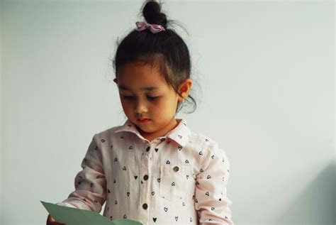 Premium Photo Innocent Girl Holding Paper Against Wall