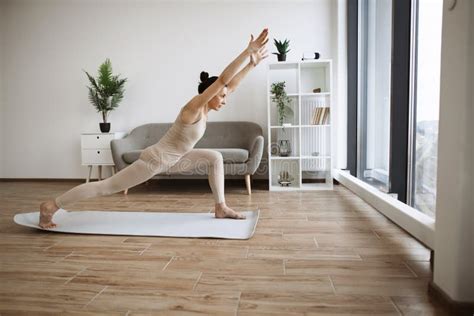 Mature Brunette Practising Warrior I Halfway Fold During Yoga Exercise