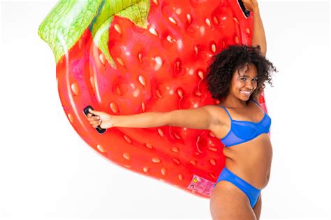 파란색 별도의 수영복을 입은 매력적인 아프리카 여성은 흰색 배경에 딸기 수영 매트리스를 보유하고 있습니다 가냘픈에 대한 스톡 사진 및 기타 이미지 Istock