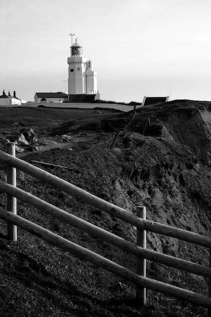 Premium Photo Lighthouse On Field By Building Against Sky