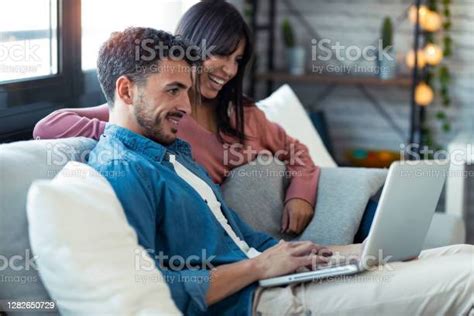 Pasangan Cantik Bahagia Menggunakan Komputer Sambil Duduk Di Sofa Di