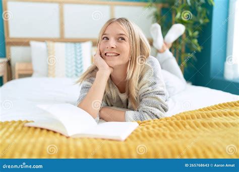Young Blonde Woman Reading Book Lying On Bed At Bedroom Stock Image