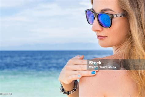 선글라스 Applyng 태양 보호 크림 푸른 하늘 아래 열 대 청록색 바다 가까운 해변에서 그녀의 손을 가진 젊은 여자 건강한 생활방식에 대한 스톡 사진 및 기타 이미지