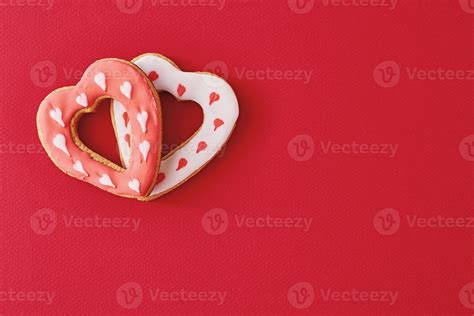 Two Decorated With Icing And Glazed Heart Shape Cookies On The Red