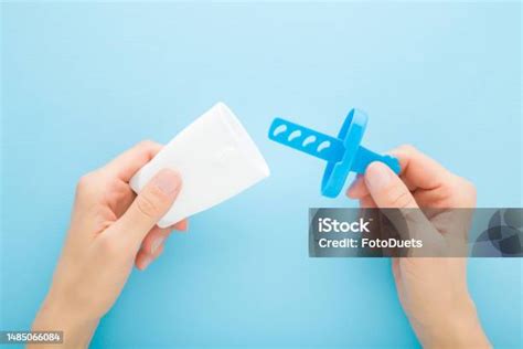 젊은 여자는 막대기에 집에서 만든 얼음 아이스 캔디를 담을 수 있는 하얀 플라스틱 용기를 들고 있다 하늘색 테이블 배경입니다