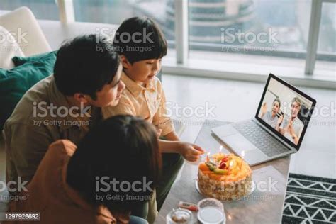 귀여운 아시아 중국 소년 점화 촛불 에 그의 생일 케이크 와 그의 부모와 조부모 사용 온라인 비디오 채팅 가족에 대한 스톡 사진