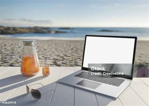 빈 흰색 화면과 바다가있는 노트북 해변의 작업장 컴퓨터 모형 무료 응용 프로그램 게임 웹 사이트 프리젠 테이션을위한 복사 공간 디자인에 맞게 준비된 빈 노트북 화면 휴가