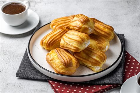 커스터드를 곁들인 프렌치 에클레어 흰색 접시에 크림을 곁들인 프로피테롤 상의 모습 크림을 곁들인 수제 패스트리 회색 배경입니다 커피를 곁들인 프로피테롤 0명에 대한 스톡