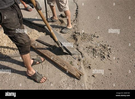 The Process Of Laying The Sidewalk Curb Workers Place A Deflected Piece Of Concrete Curb Into A