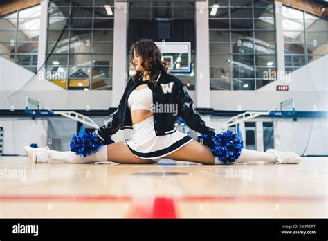 Front View Of A Brunette Cheerleader Holding Blue Shiny Pom Poms And