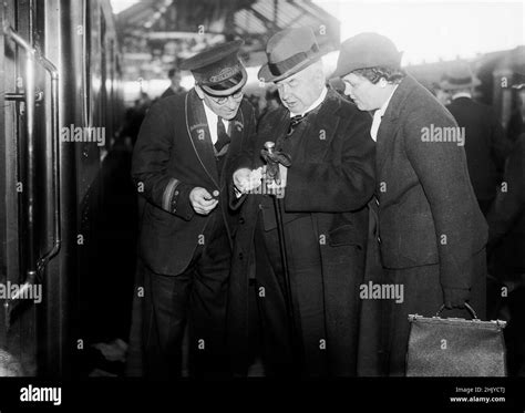 A Railway Attendant On A Pullman Car Inspects The Tickets Of Two Passengers At A Station In